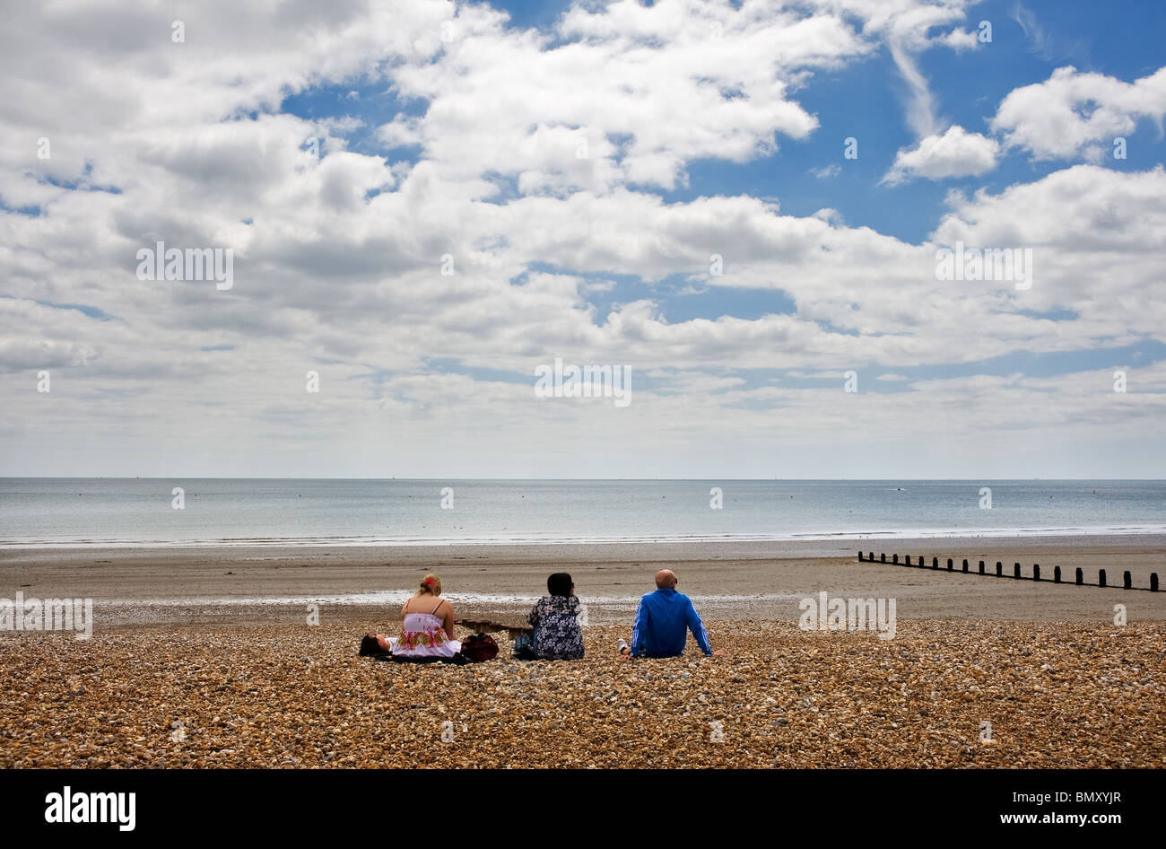 Three people relaxing on a beach. Photo by Gordon Scammell Stock Photo ...