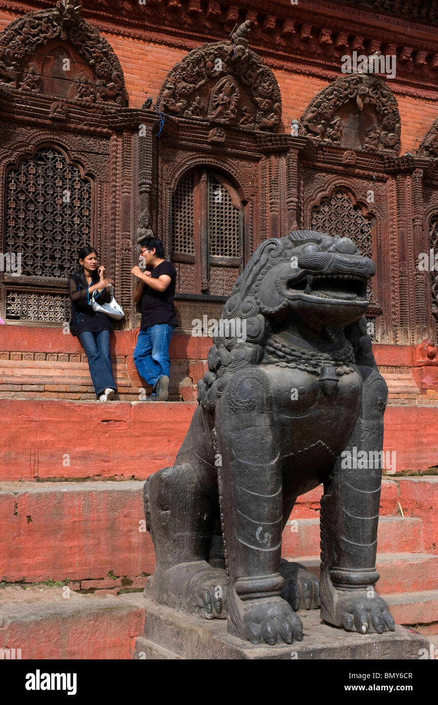 The bronze Temple Guard lion with his back turned to a young couple at ...