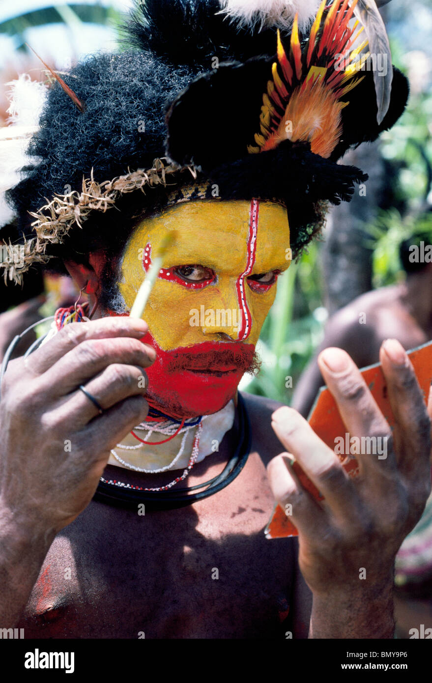 A Huli Wigman paints his face in bright colors for a traditional sing ...