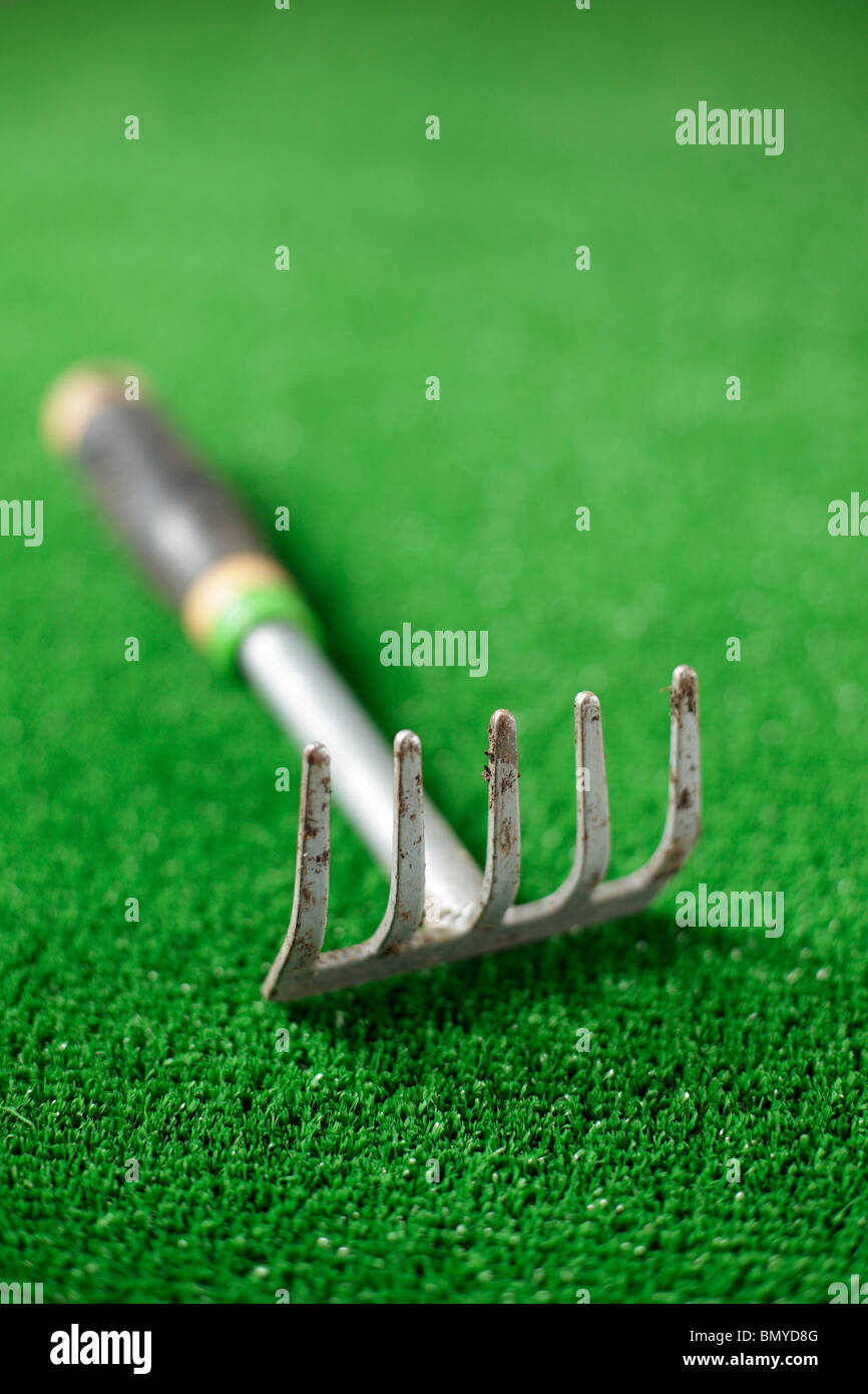 A small rake, tool for the gardening, on an artificial grass, studio ...