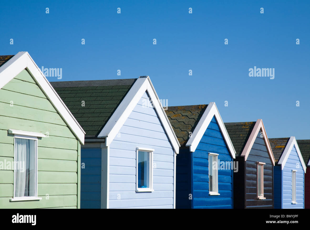 row of colorful beach huts under blue sky Stock Photo - Alamy