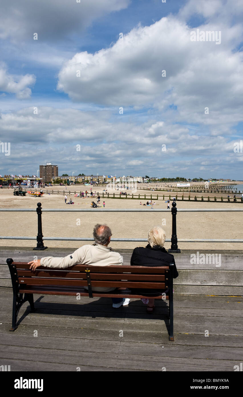 People holidaymakers sitting bench relaxing seat beach breakwaters ...