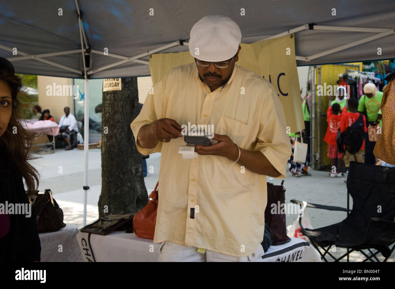 A vendor processes a wireless credit card transaction at a street fair ...