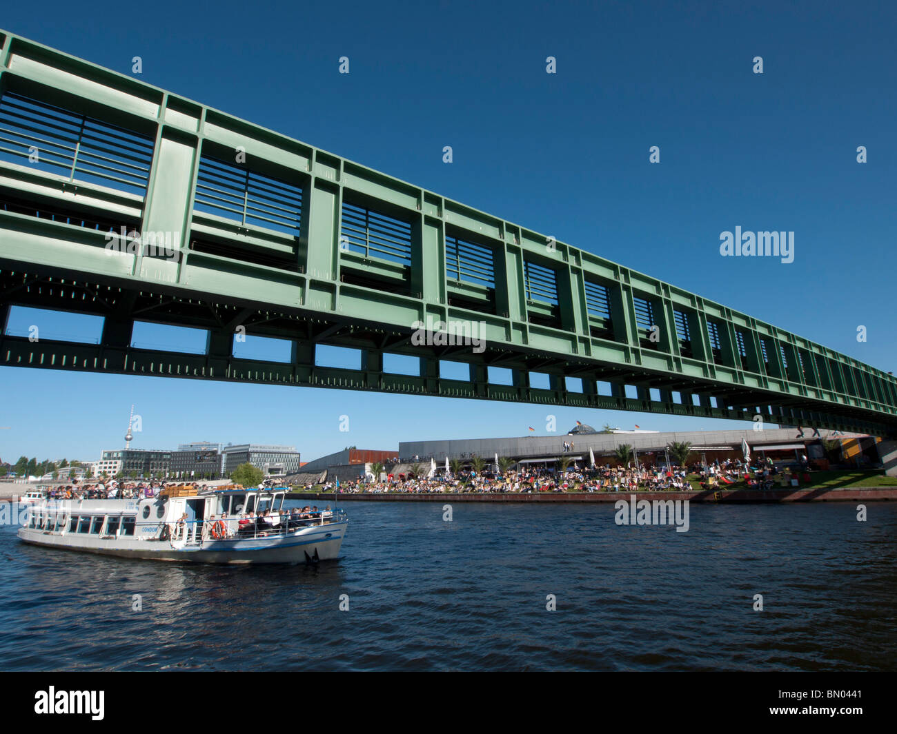 modern footbridge across Spree River with busy riverside bar to rear in ...