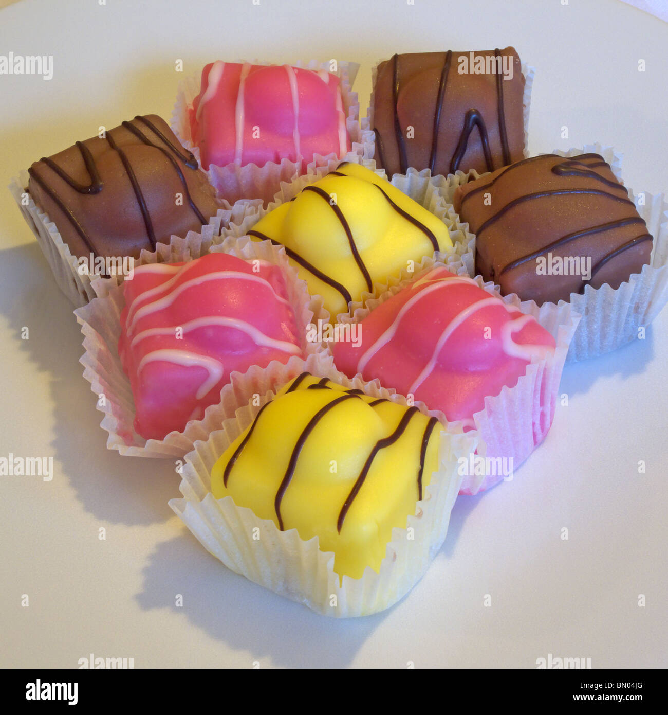 Individual Fondant Fancies (Small Iced Cakes) on a White Plate Stock ...