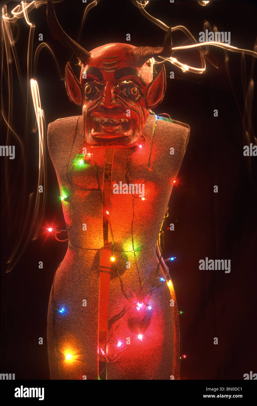 Holiday lights on mannequin with devil mask Stock Photo - Alamy