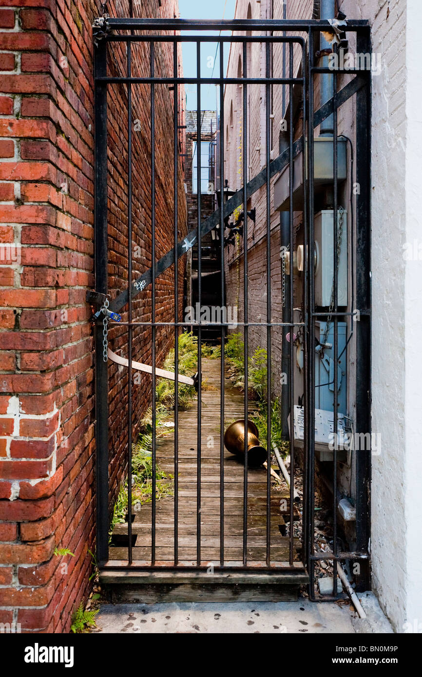 Locked black wrought iron gate secures alley between brick buildings in ...