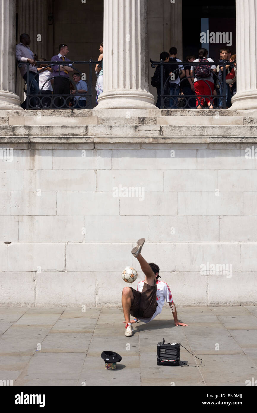 A young busker performs football skills on the pavement outside the ...