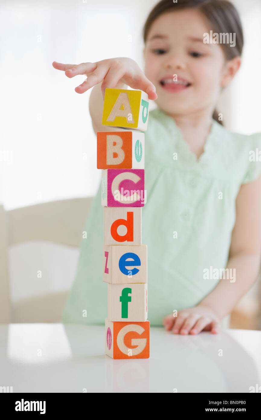Mixed race girl stacking alphabet blocks Stock Photo - Alamy
