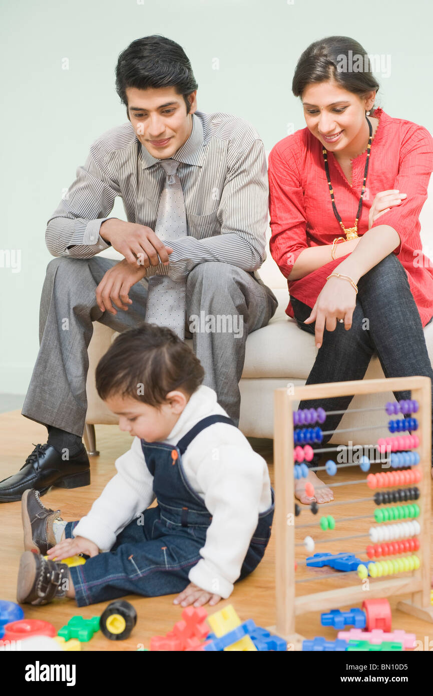 Couple looking at their son playing with toys Stock Photo - Alamy