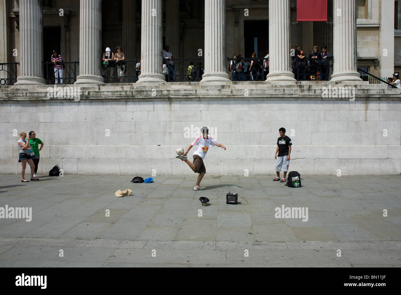 A young busker performs football skills on the pavement outside the ...