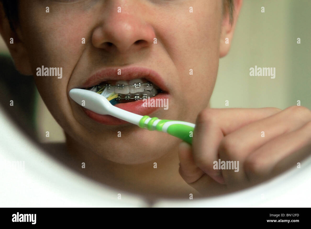 Teenage boy with dental braces brushing teeth in mirror Stock Photo - Alamy