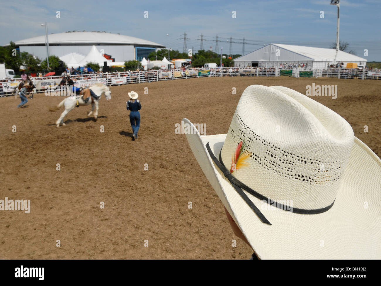 A young rodeo spectator with a cowboy hat watches a bucking bronco ...