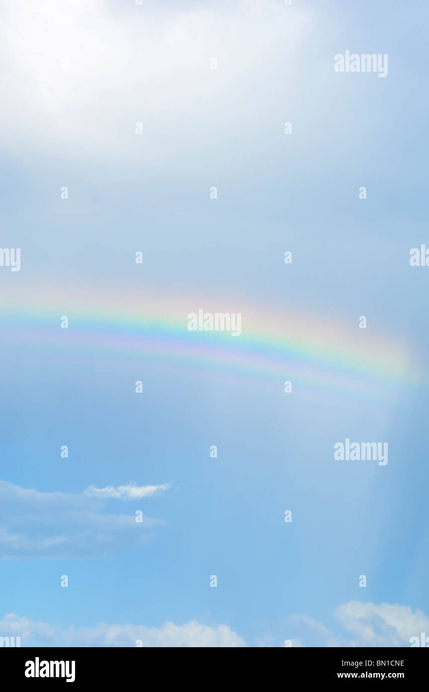 Rainbow in blue sky with few clouds Stock Photo - Alamy