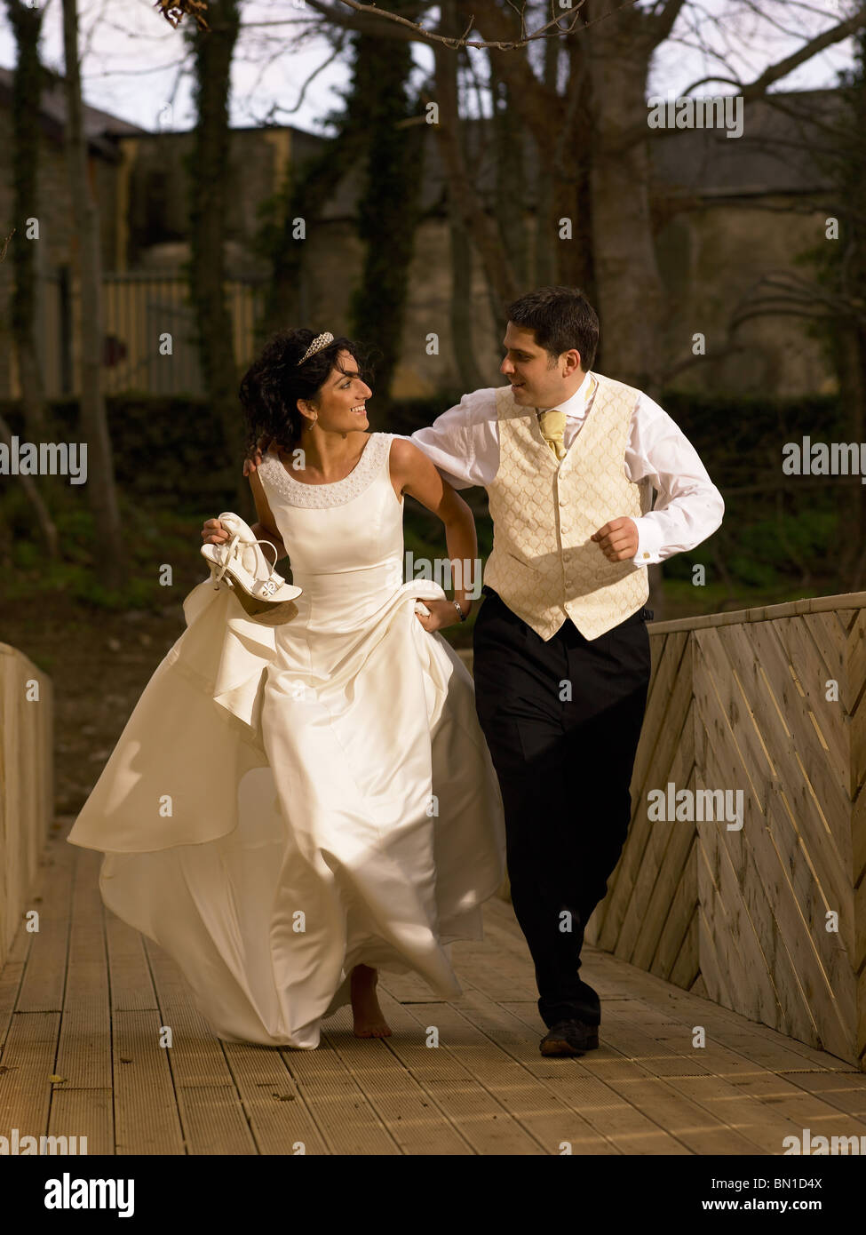 Bride & Groom running across a bridge Stock Photo - Alamy