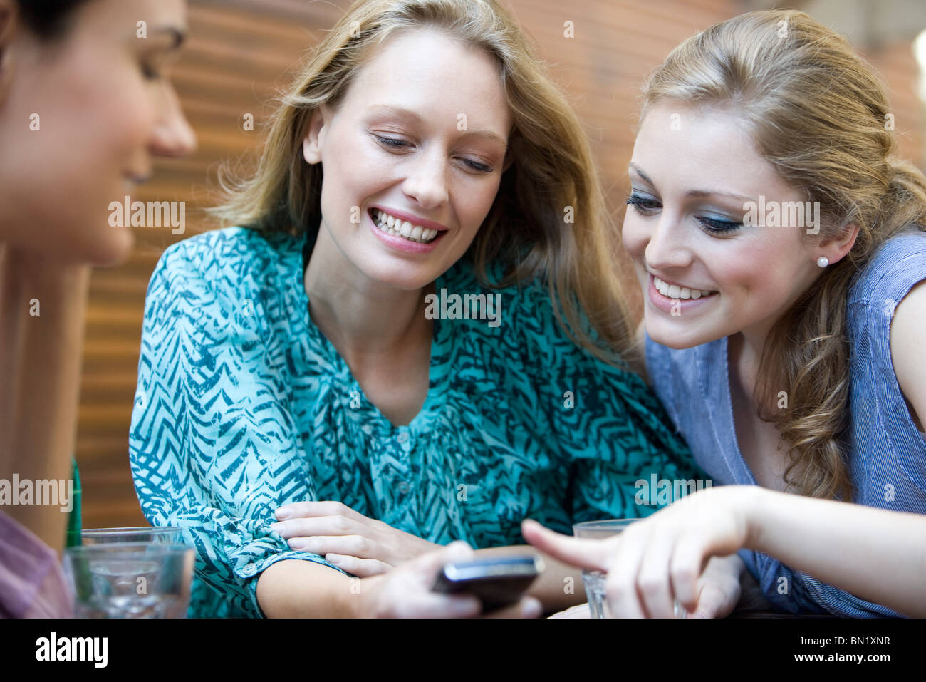 Young woman showing cell phone to friends Stock Photo - Alamy