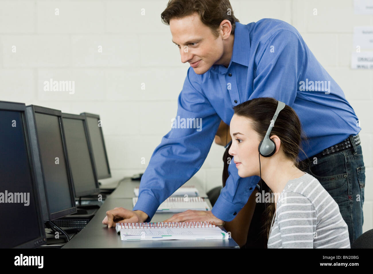 Teacher assisting student in computer lab Stock Photo - Alamy