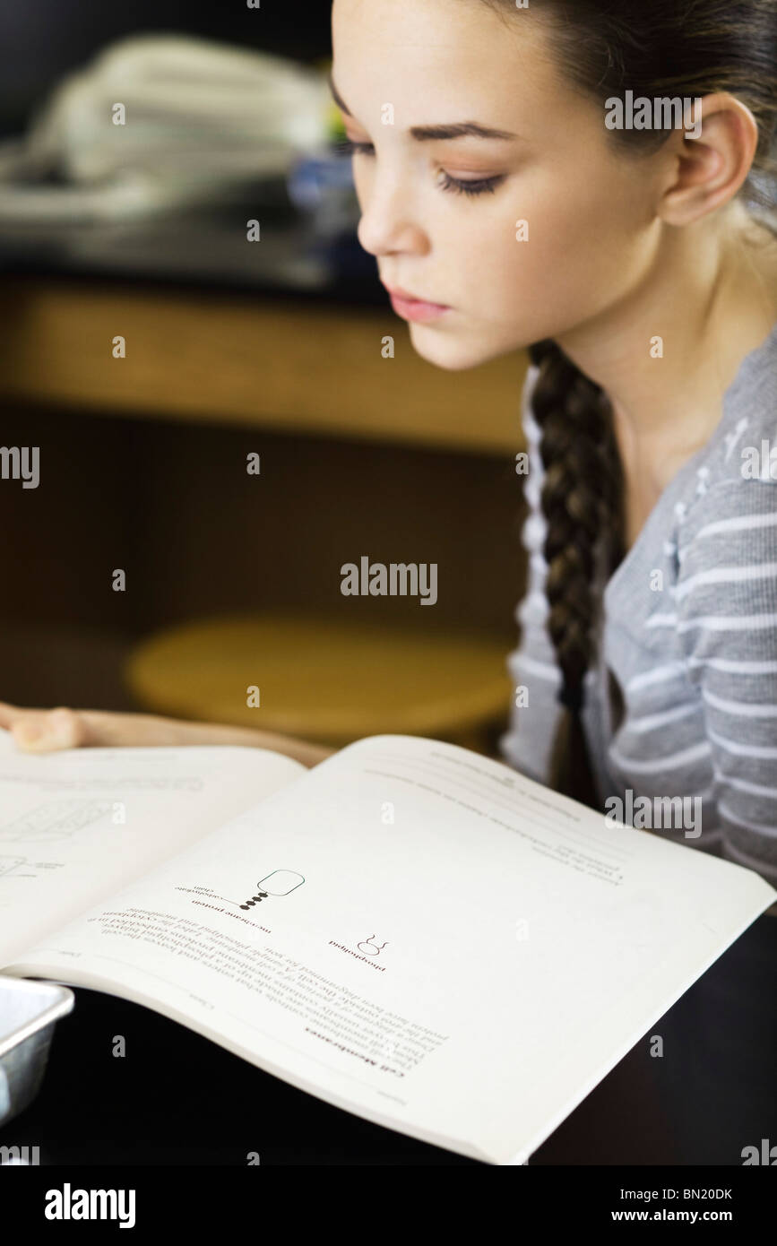 Female student reading textbook Stock Photo - Alamy