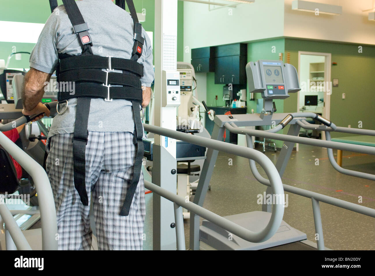 Man exercising on treadmill with assistance of rehabilitation harness ...