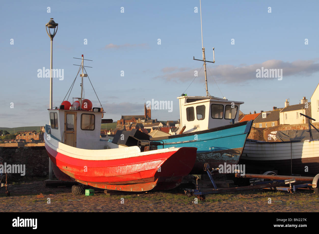 Berthed boats in Dunbar on a summer morning, with a church tower in the ...
