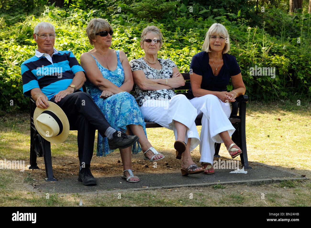 Four pensioners sat on a park bench one man and three women Stock Photo ...