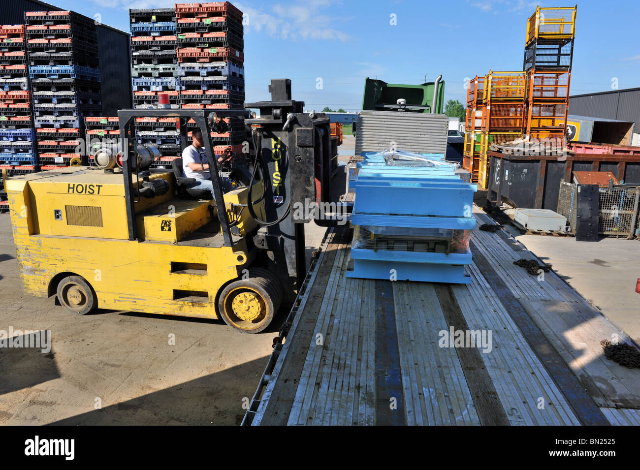person using a fork lift to load freight onto a flatbed semi trailer ...