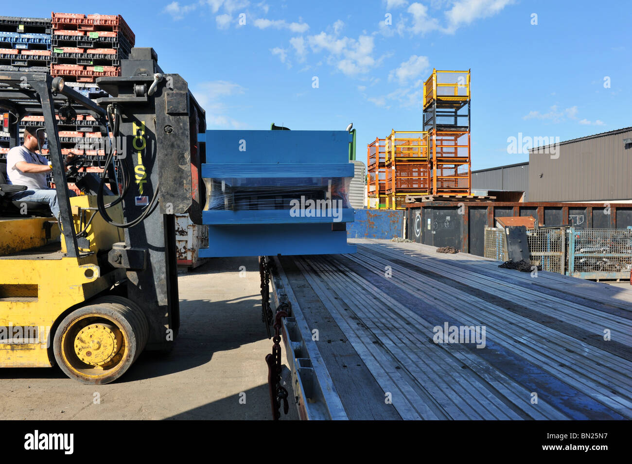 person using a fork lift to load freight onto a flatbed semi trailer ...
