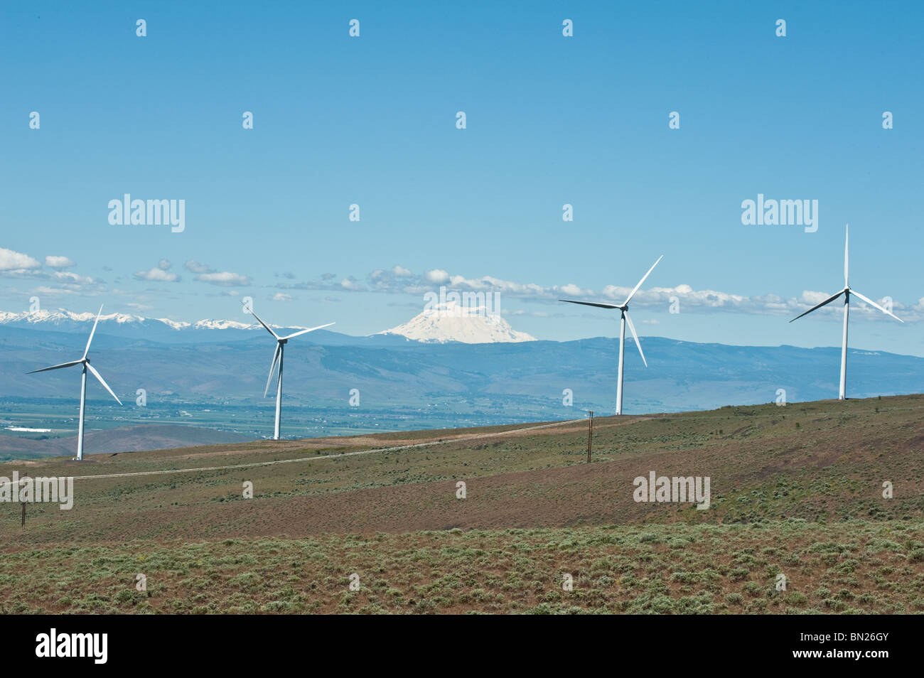 Giant clean energy wind turbines on a mountain ridge with a snow capped ...