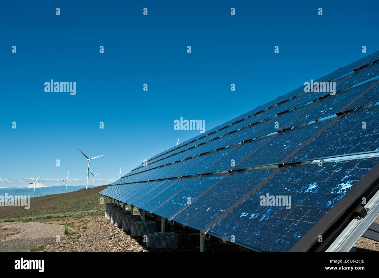 Giant clean energy wind turbines and a solar panel on a mountain ridge ...