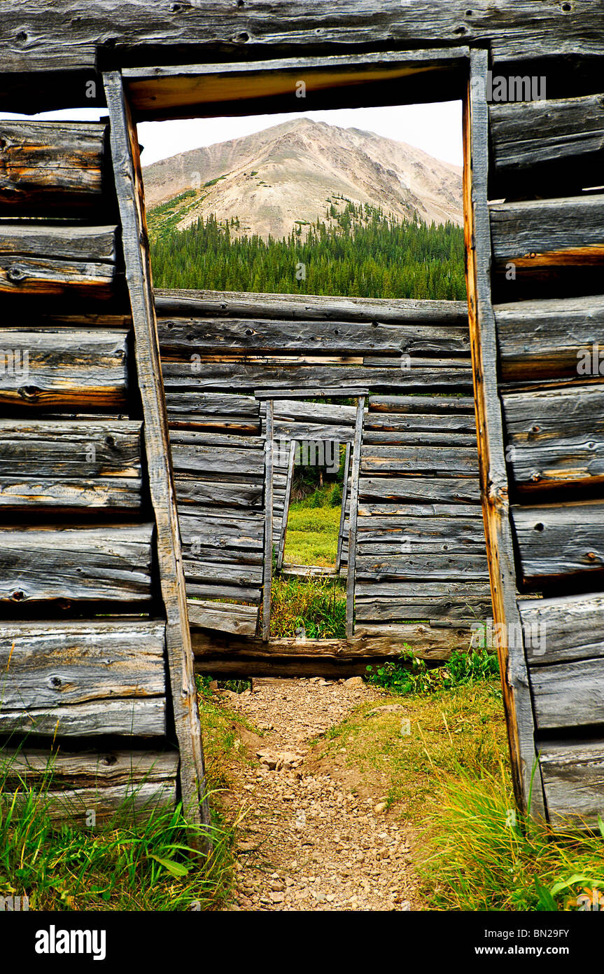Looking through doors of a log cabin towards mountain in the distance ...