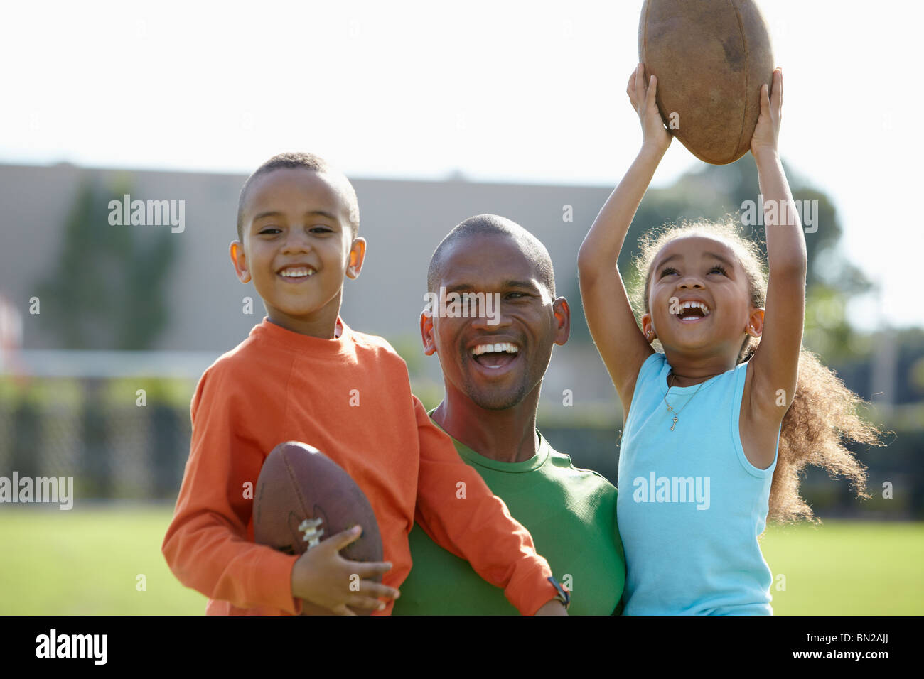 African American father, son and daughter playing football Stock Photo ...