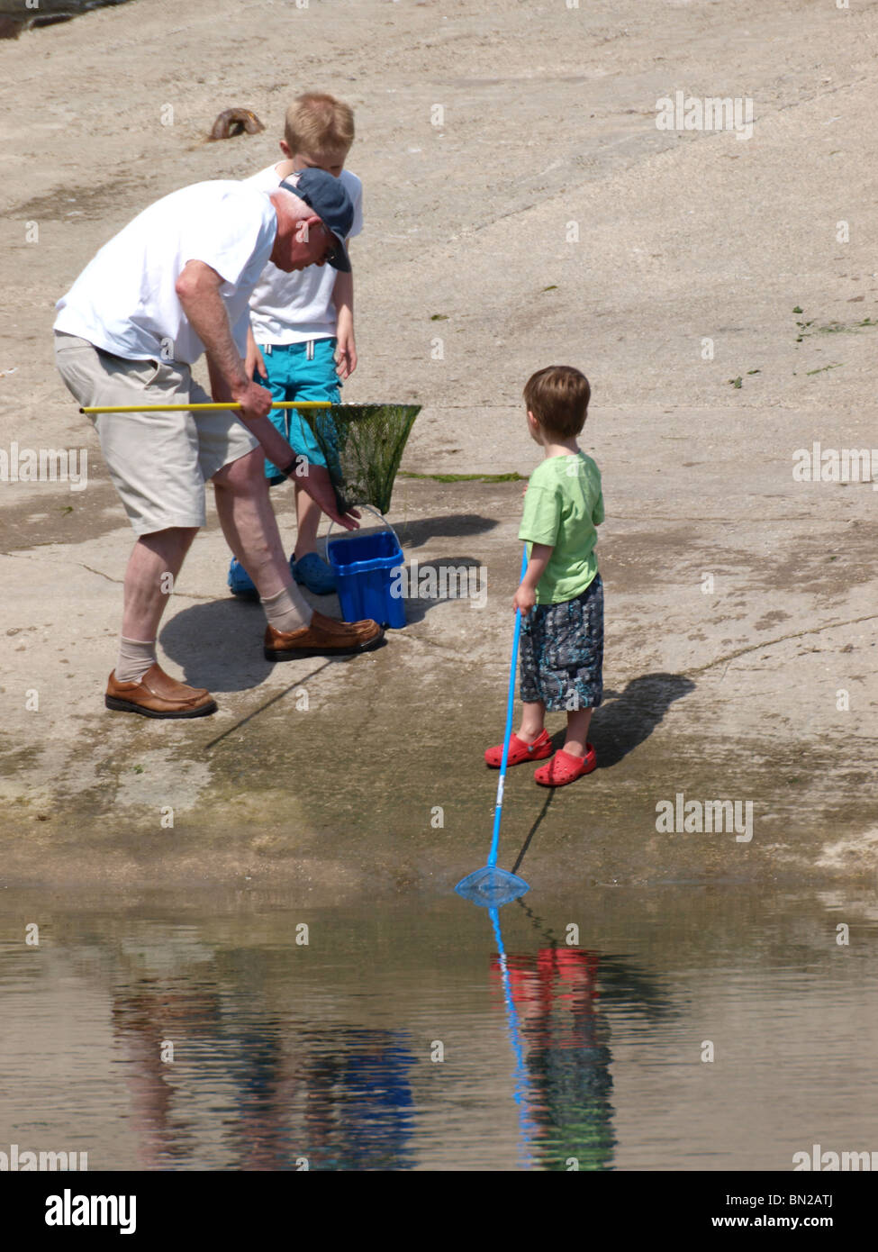 Granddad with children catching things in Padstow harbour, Cornwall, UK ...
