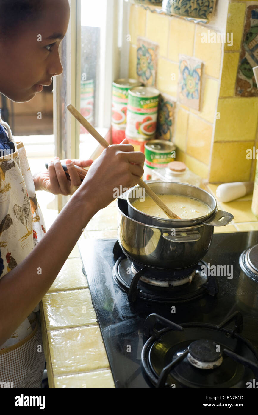 Girl stirring pot on stove Stock Photo - Alamy