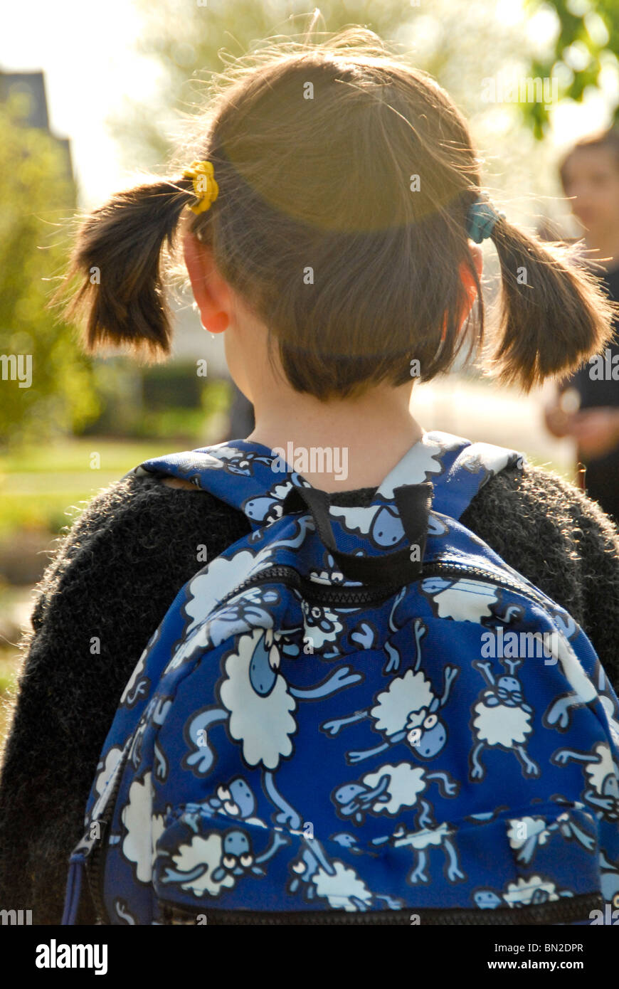 Young girl walking to school wearing a backpack Stock Photo - Alamy