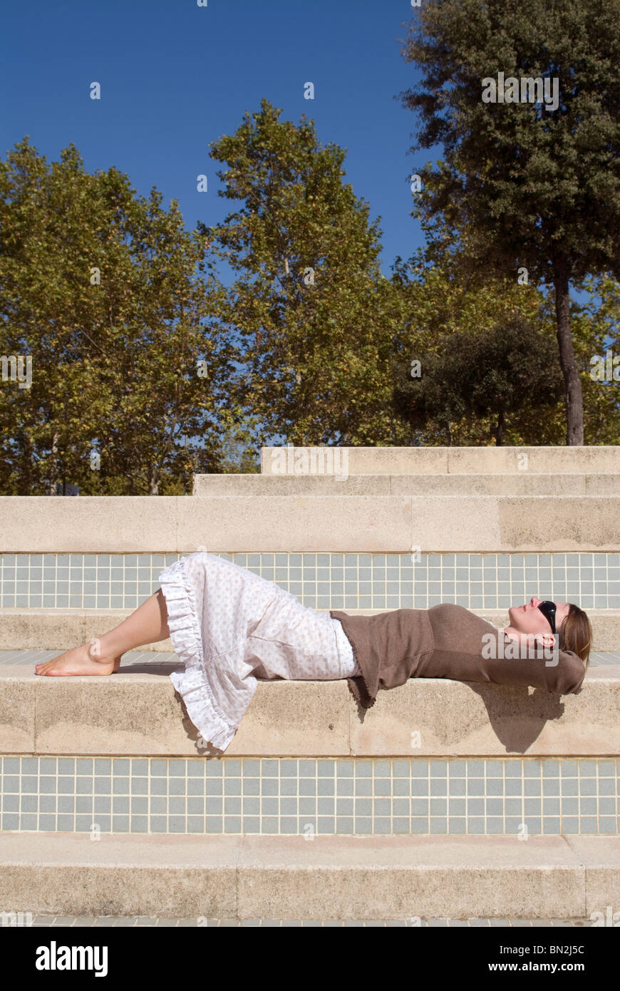 Woman lying down on a step and relaxing in the sun Stock Photo - Alamy