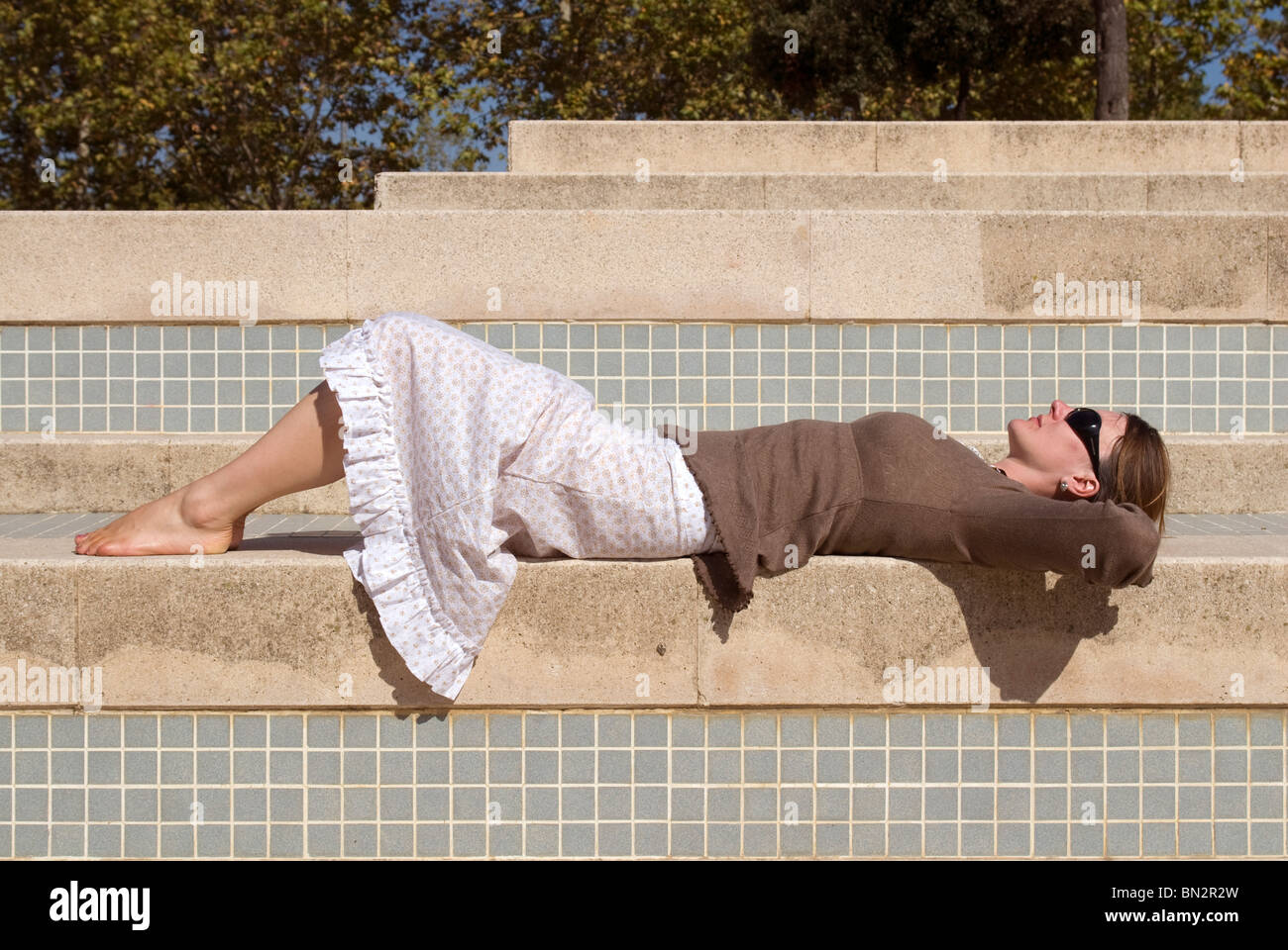 Woman lying down on a step and relaxing in the sun Stock Photo - Alamy