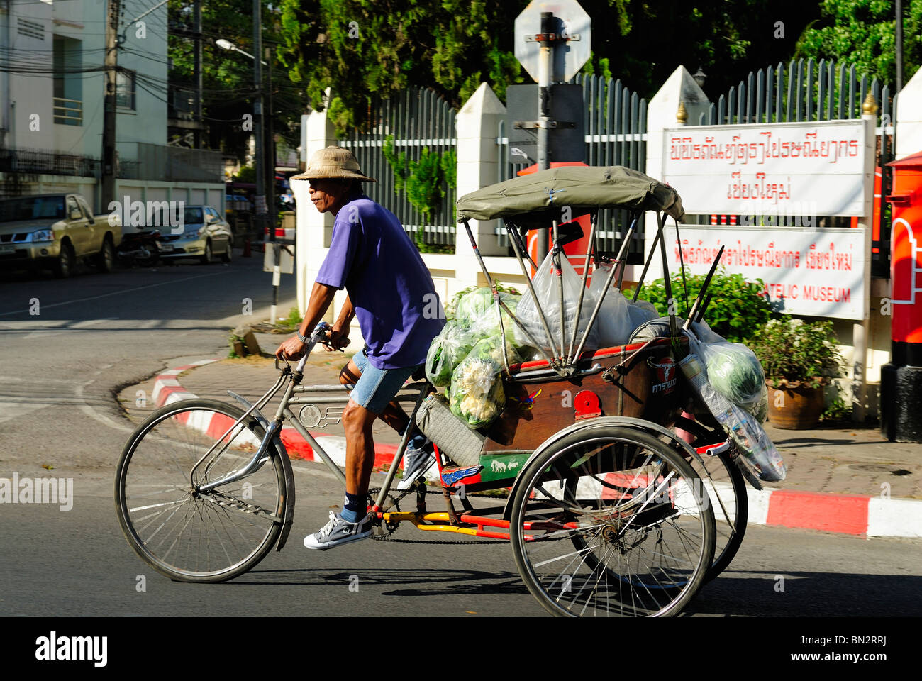 Thai man riding a bicycle taxi and carrying food in a street in Chiang ...