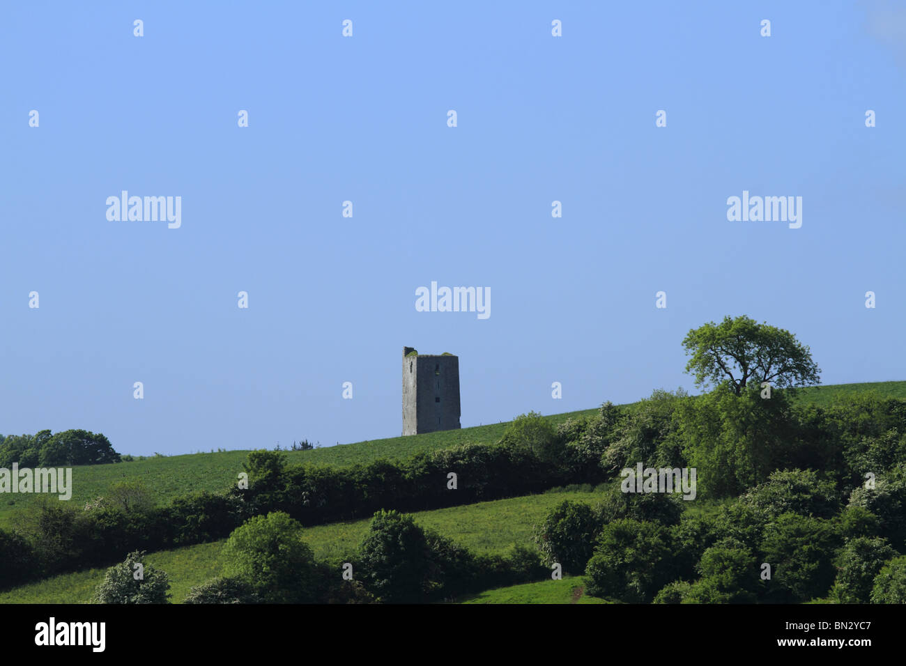 An old Irish Tower House on the crest of a hill overlooks the farmland ...