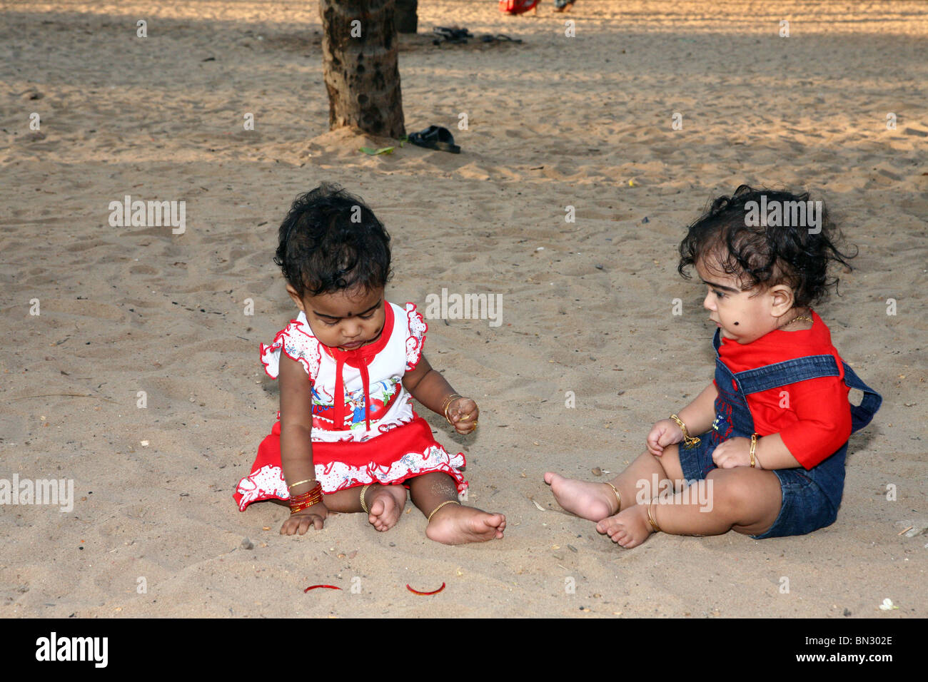 Two babies playing with sand Stock Photo - Alamy