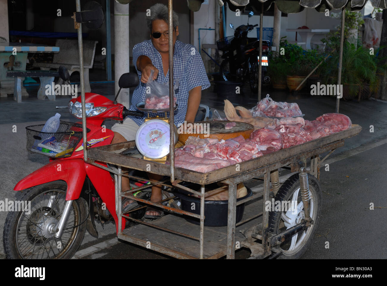 Hawker riding a sidecar with a meat booth in Baan Nam Khen village ...