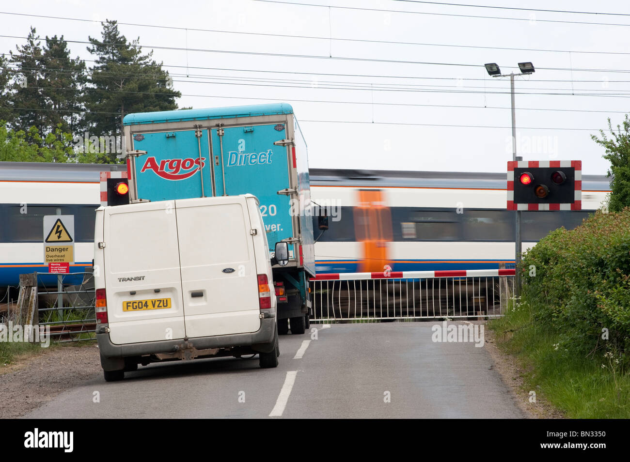 Traffic waiting as high speed passenger train passes through a level ...