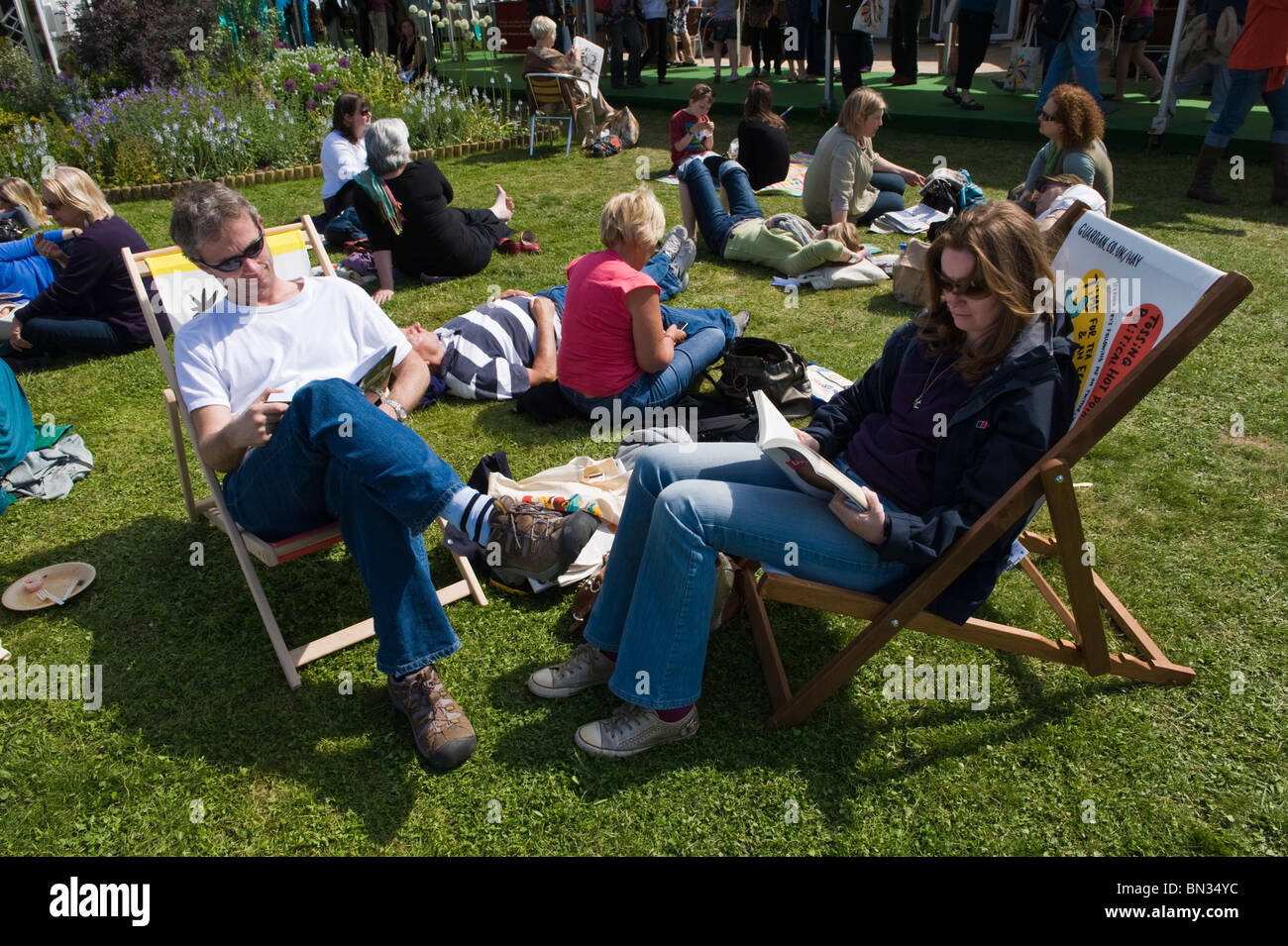 People reading books sitting in deckchairs amongst the crowd in the ...