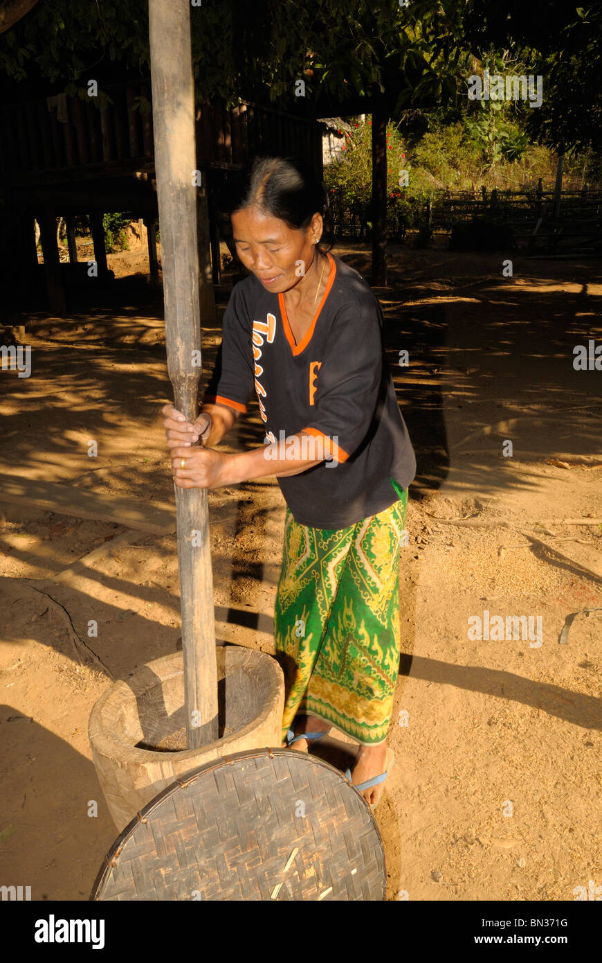 Portrait of a woman using a pestle in the backyard of her house in a ...