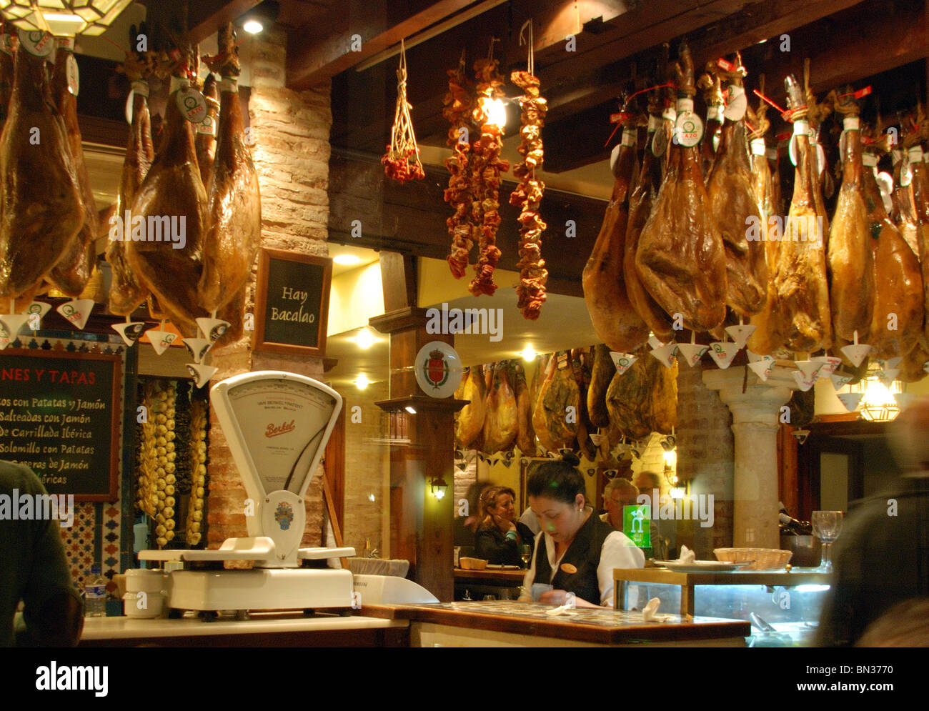 Jamon Serrano hanging above a tapas bar counter, Santa Cruz district ...