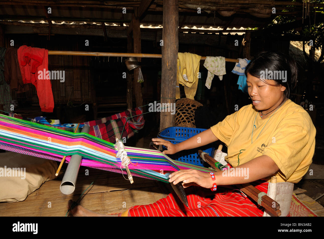 Portrait of a Palong woman using a weaving-loom and wearing traditional ...