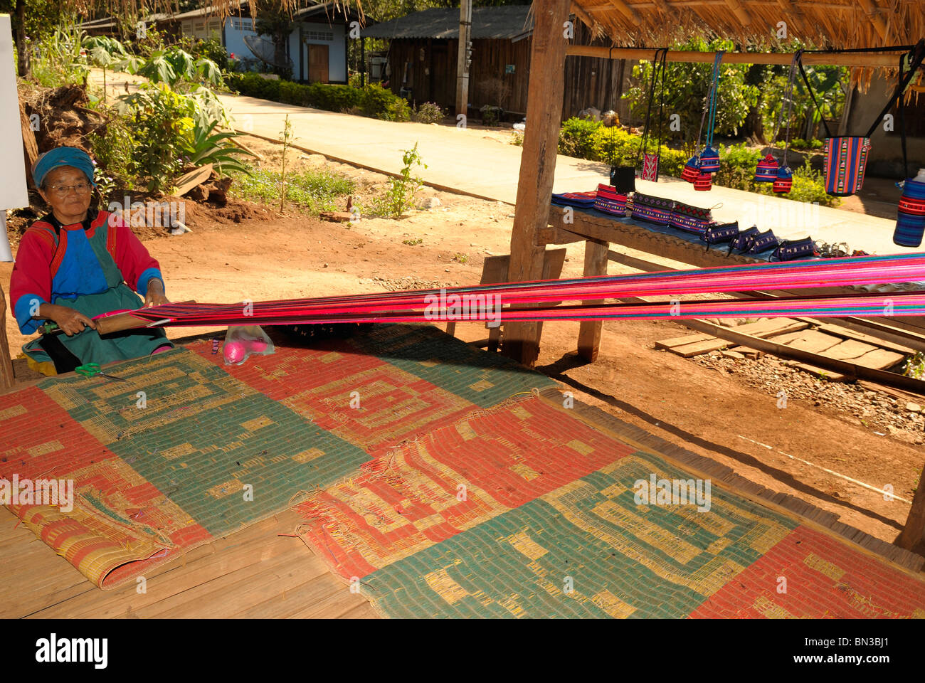 Portrait of a Lisu woman using a weaving-loom and wearing traditional ...