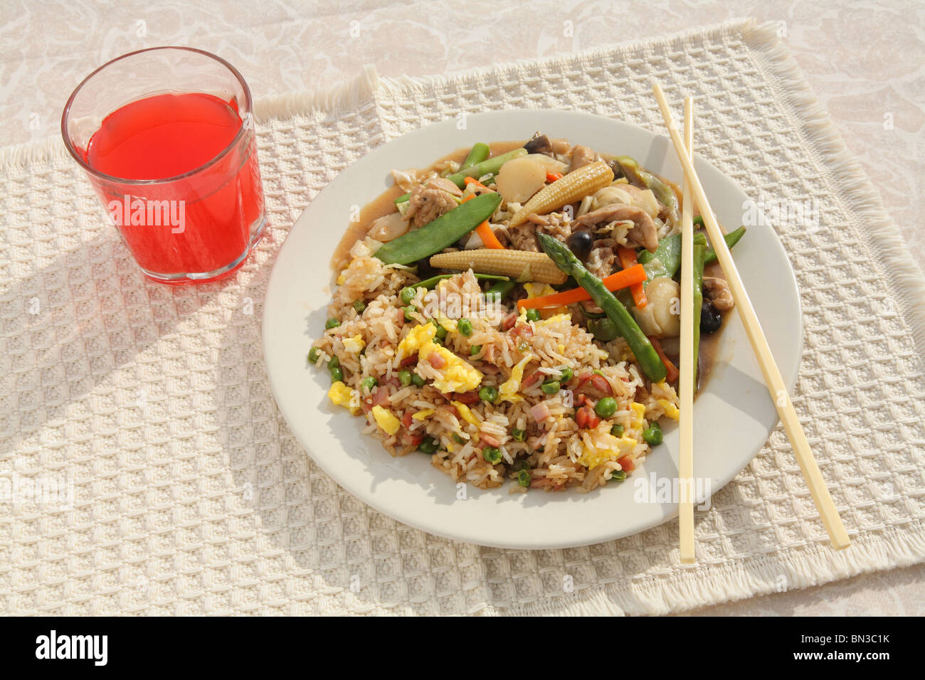 table setting with Chinese chicken stir-fry, chopsticks and red drink ...