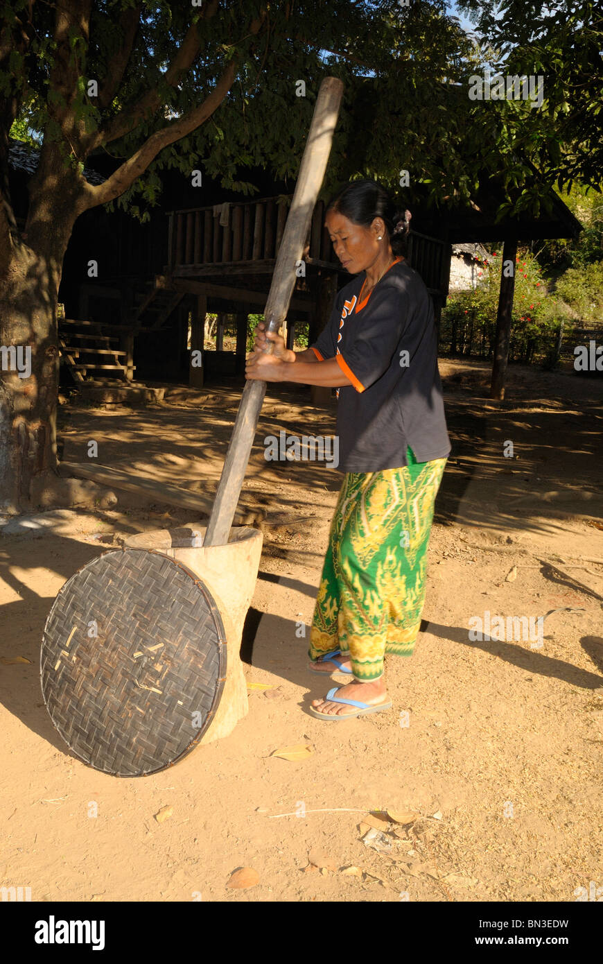 Portrait of a woman using a pestle in the backyard of her house in a ...