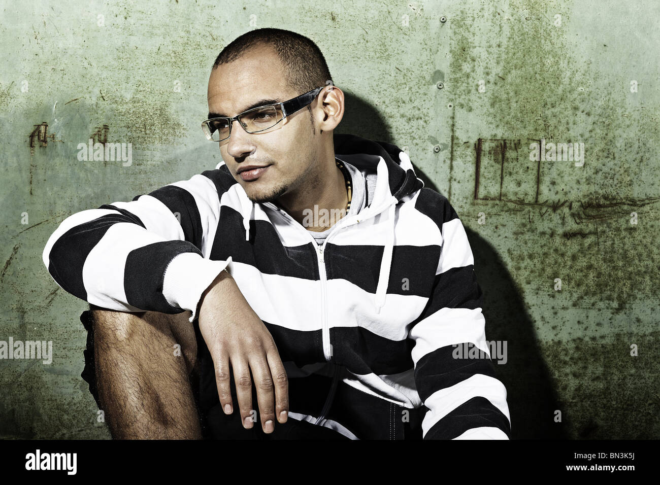 Young man sitting in front of a gate, portrait Stock Photo - Alamy