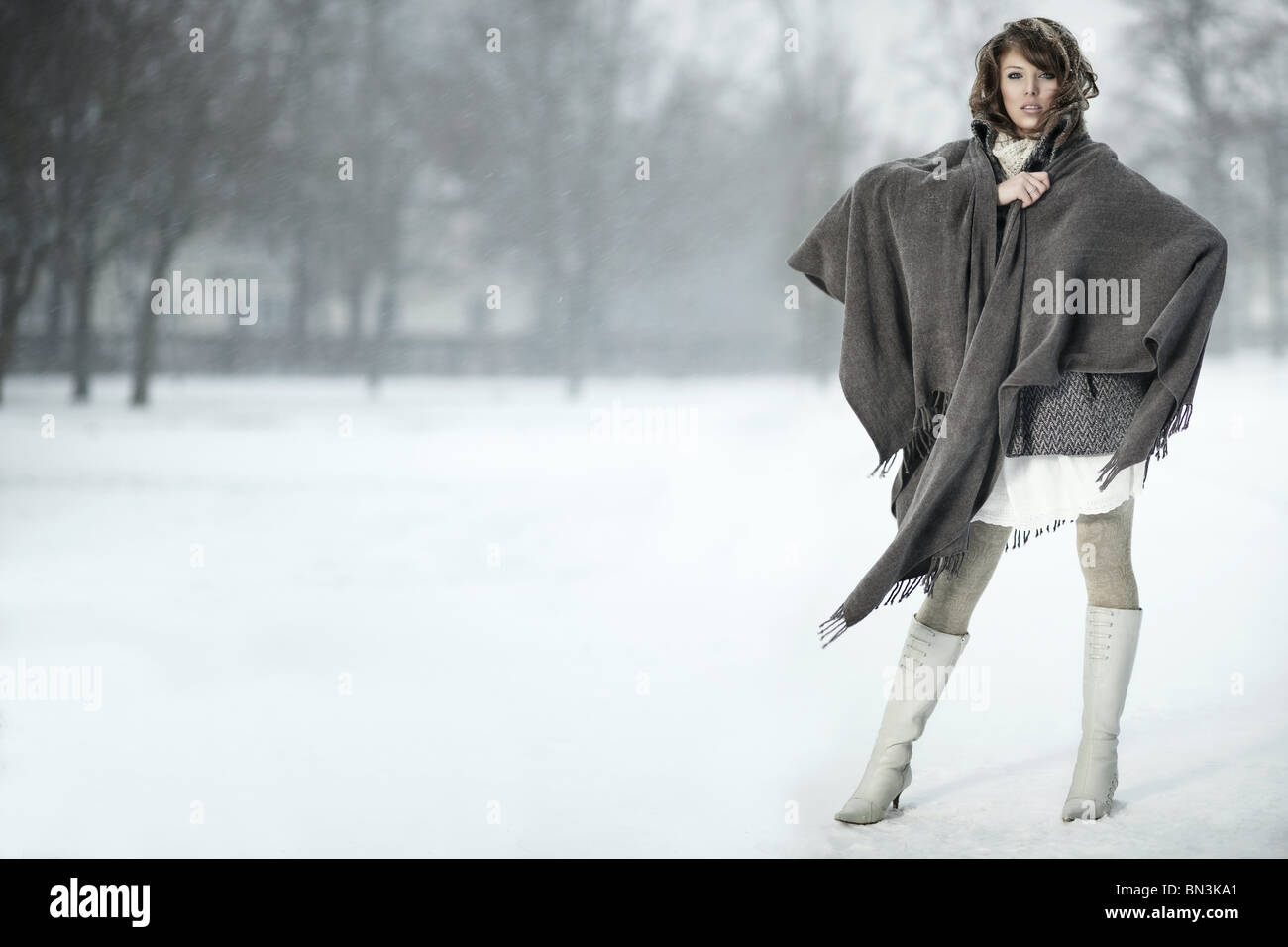 Young woman standing with poncho in snow Stock Photo - Alamy